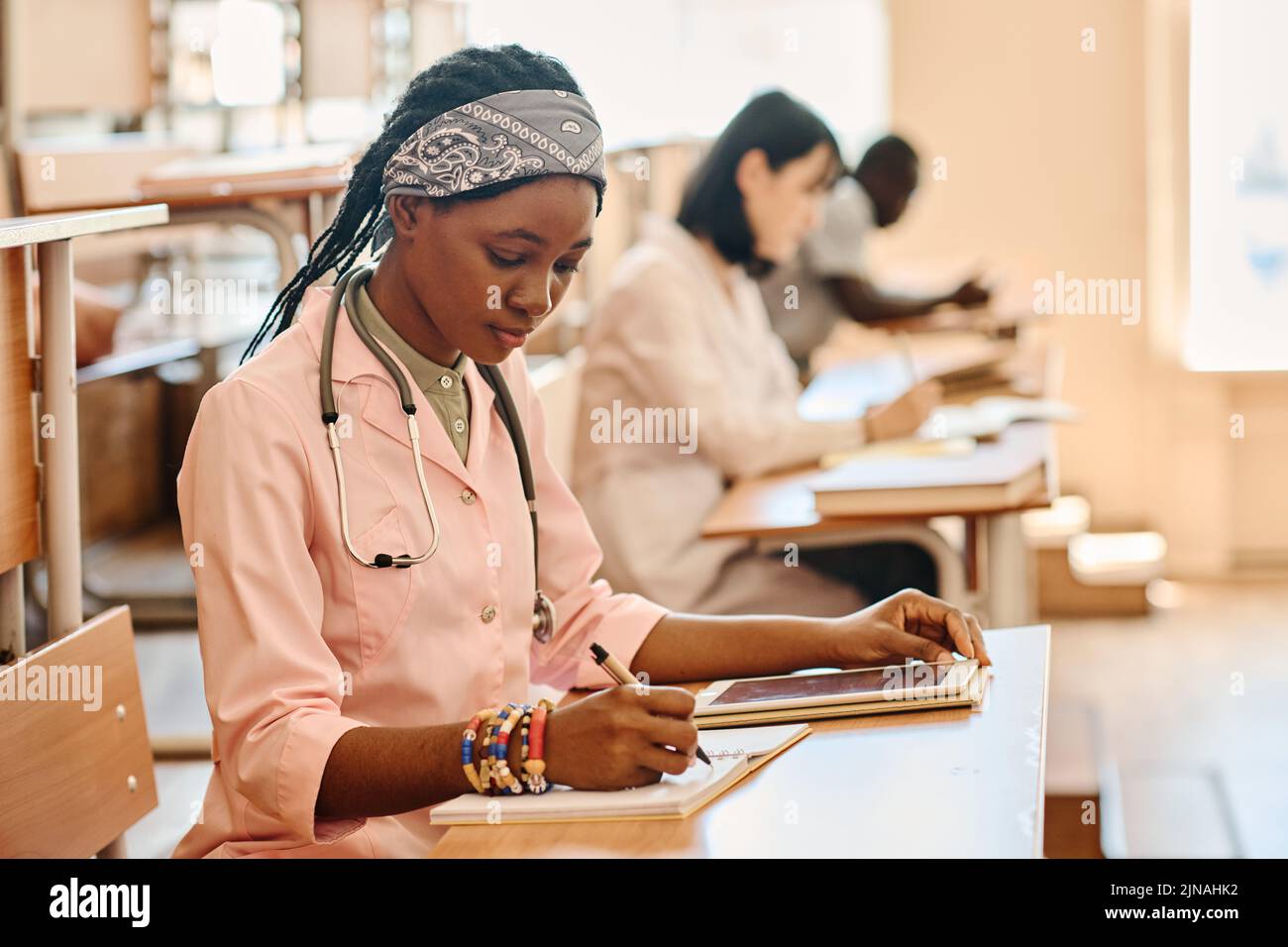 African medical student in uniform studying at university, she sitting ...