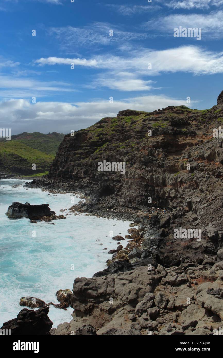 A cliffside composed of volcanic rock lining the Pacific Ocean on a ...
