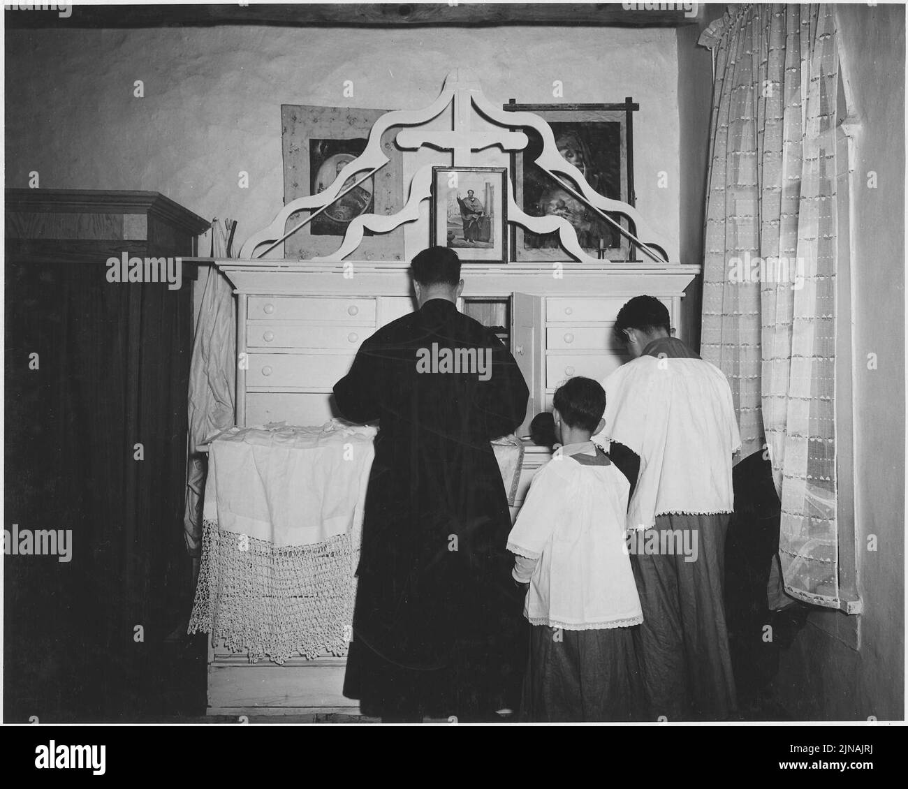 Taos County, New Mexico. Father Morgan puts on vestments for Mass in ...