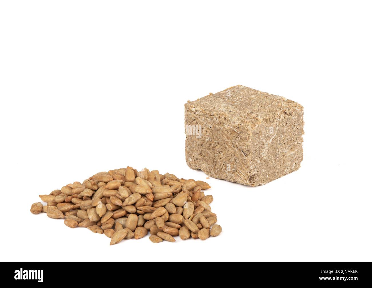A piece of sunflower halva and peeled sunflower seeds on a white background. Halva is a kind of ...