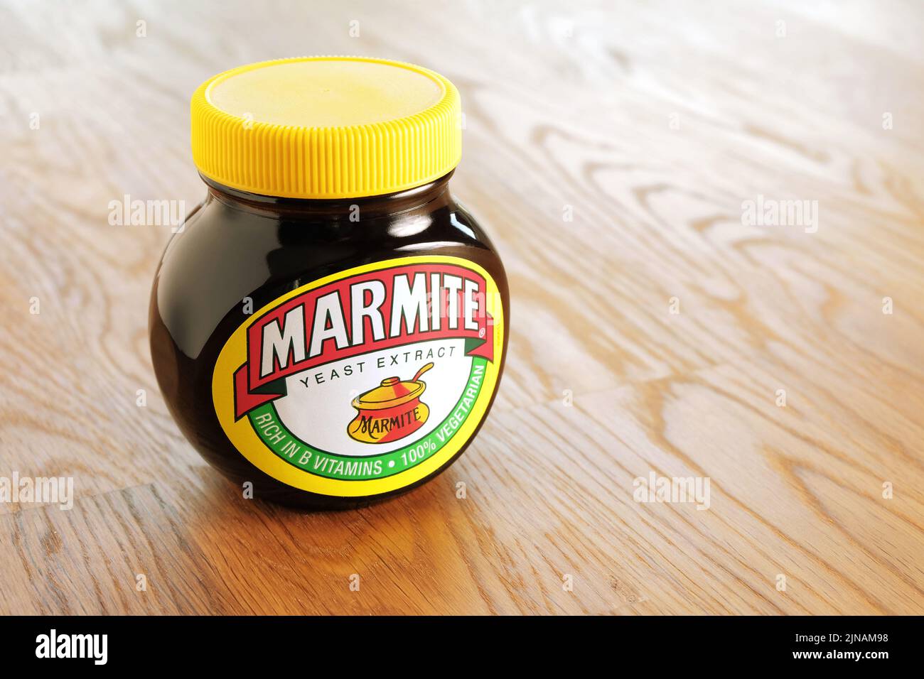 Jar of Marmite, unopened on wooden table top. Marmite is a food paste ...