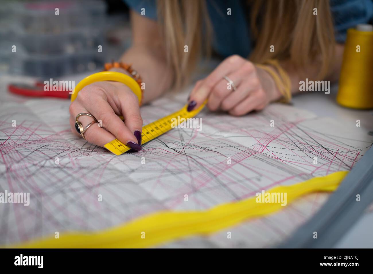 A clothing designer measures with a tailor's centimeter on a sheet of ...