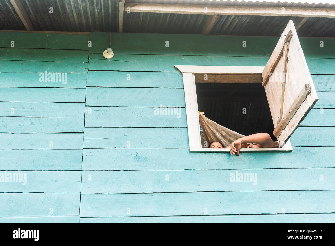 Indigenous family showing themselves through the window of their wooden ...