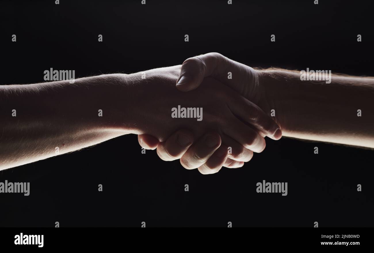 Photo of two men shaking hands on a black background Stock Photo - Alamy