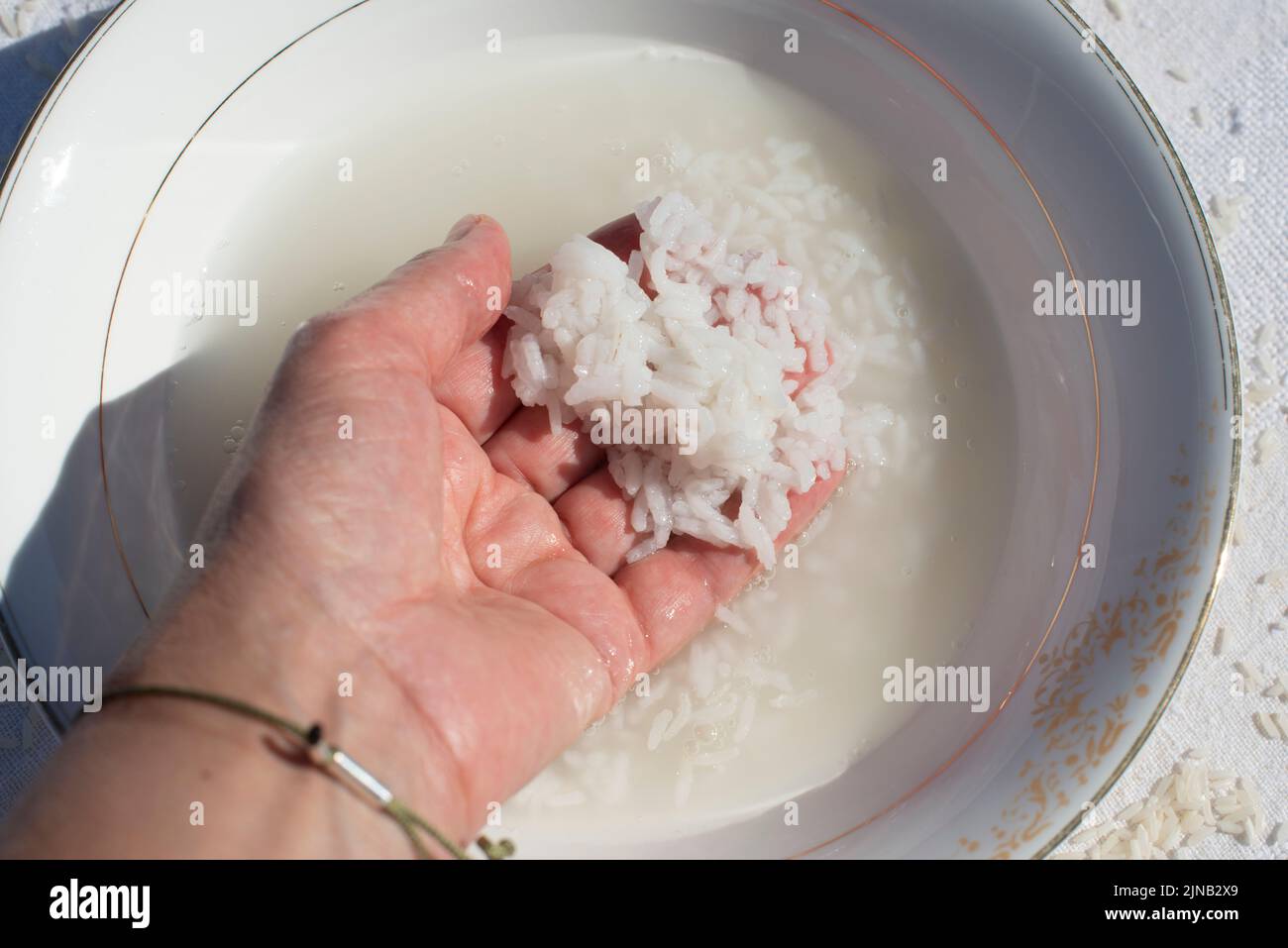 Rice grains in hand, rice water preparation Stock Photo - Alamy