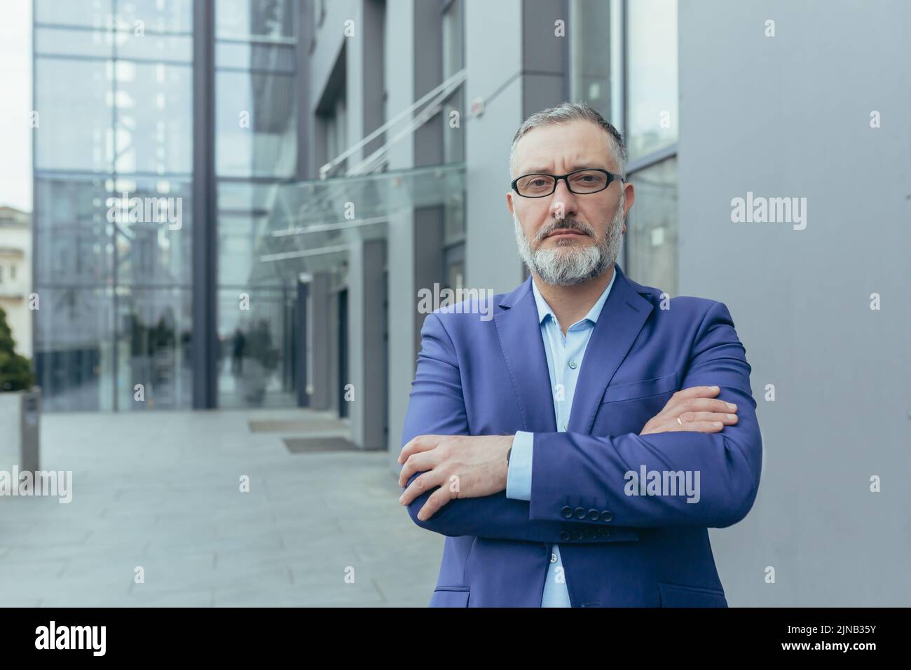 Portrait of serious senior gray-haired investor, man with crossed arms ...