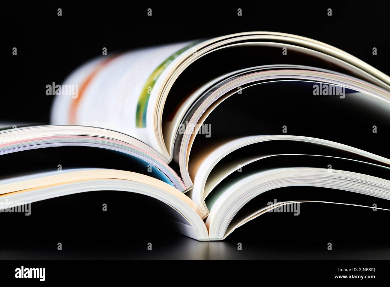 A part of a stack of open magazines on dark background Stock Photo - Alamy