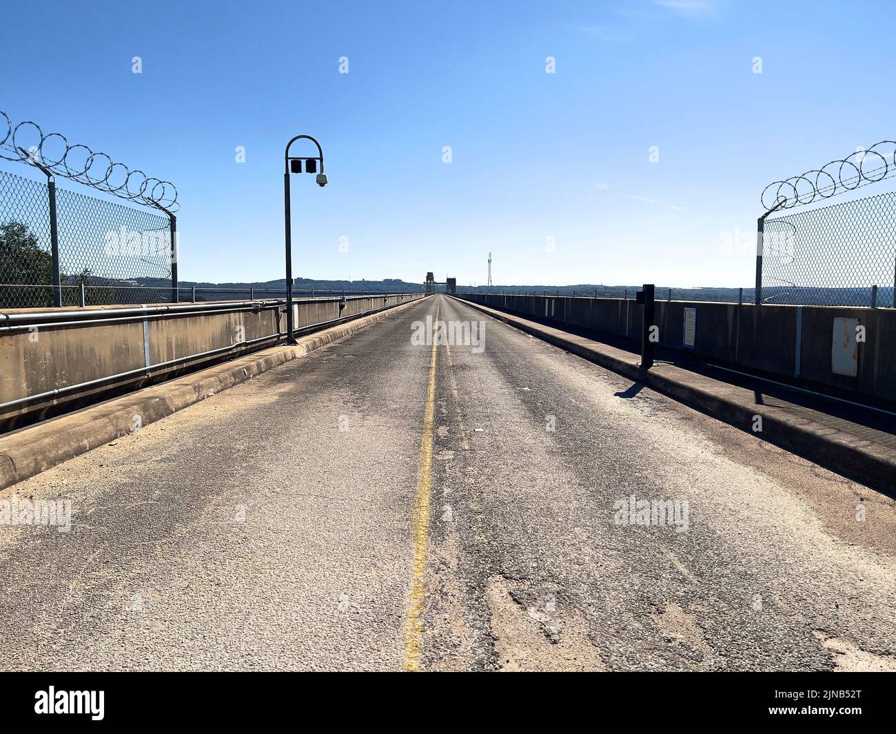 The road with fence with concertina razor wires under the blue sky ...