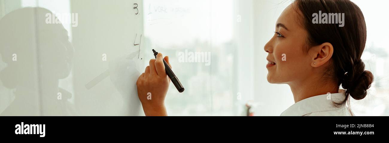 Smiling asian business woman write project plan on flipboard during ...