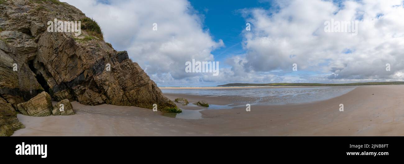 A panorama landscape view of Maghera Beach with the entrance to one of ...