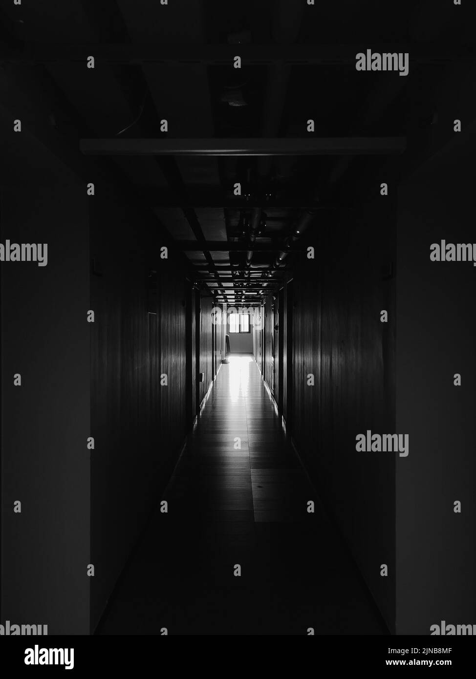 the vertical grayscale of windows at the end of a dark narrow corridor ...