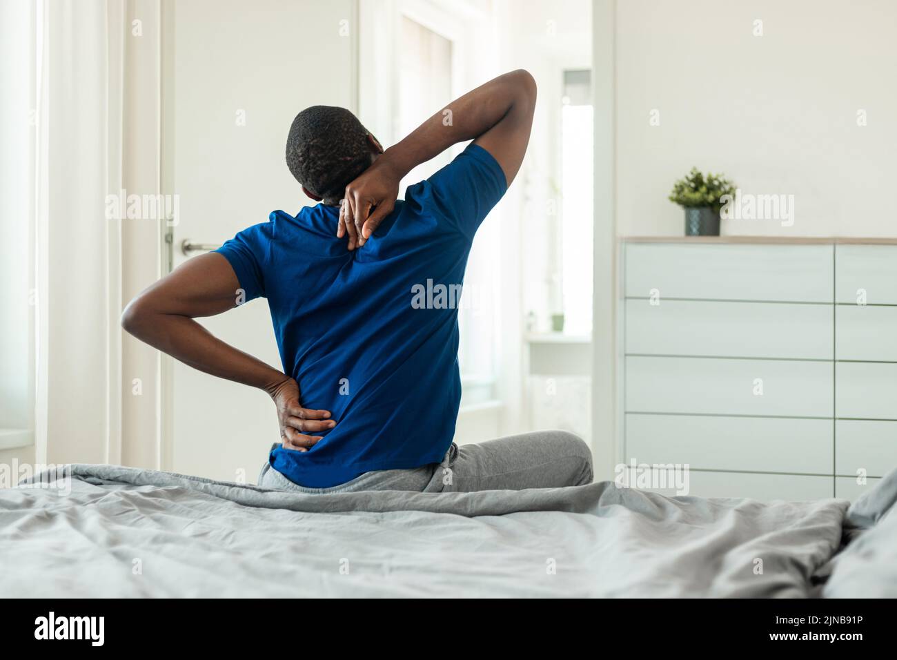 African Man Touching Aching Neck And Spine Sitting In Bedroom Stock ...