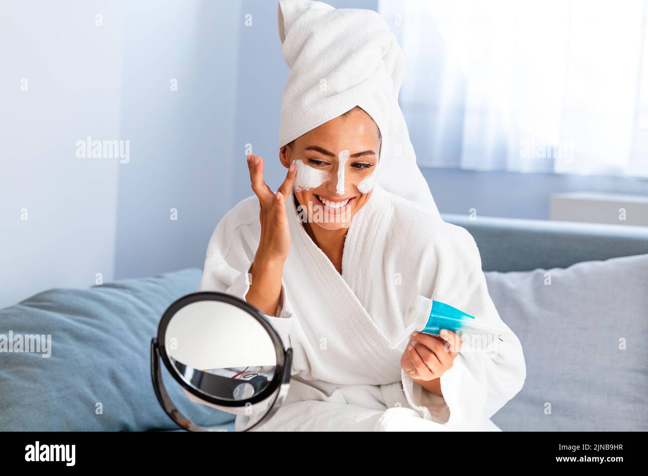 Young beautiful woman applying homemade facial mask i at home.Skin care ...