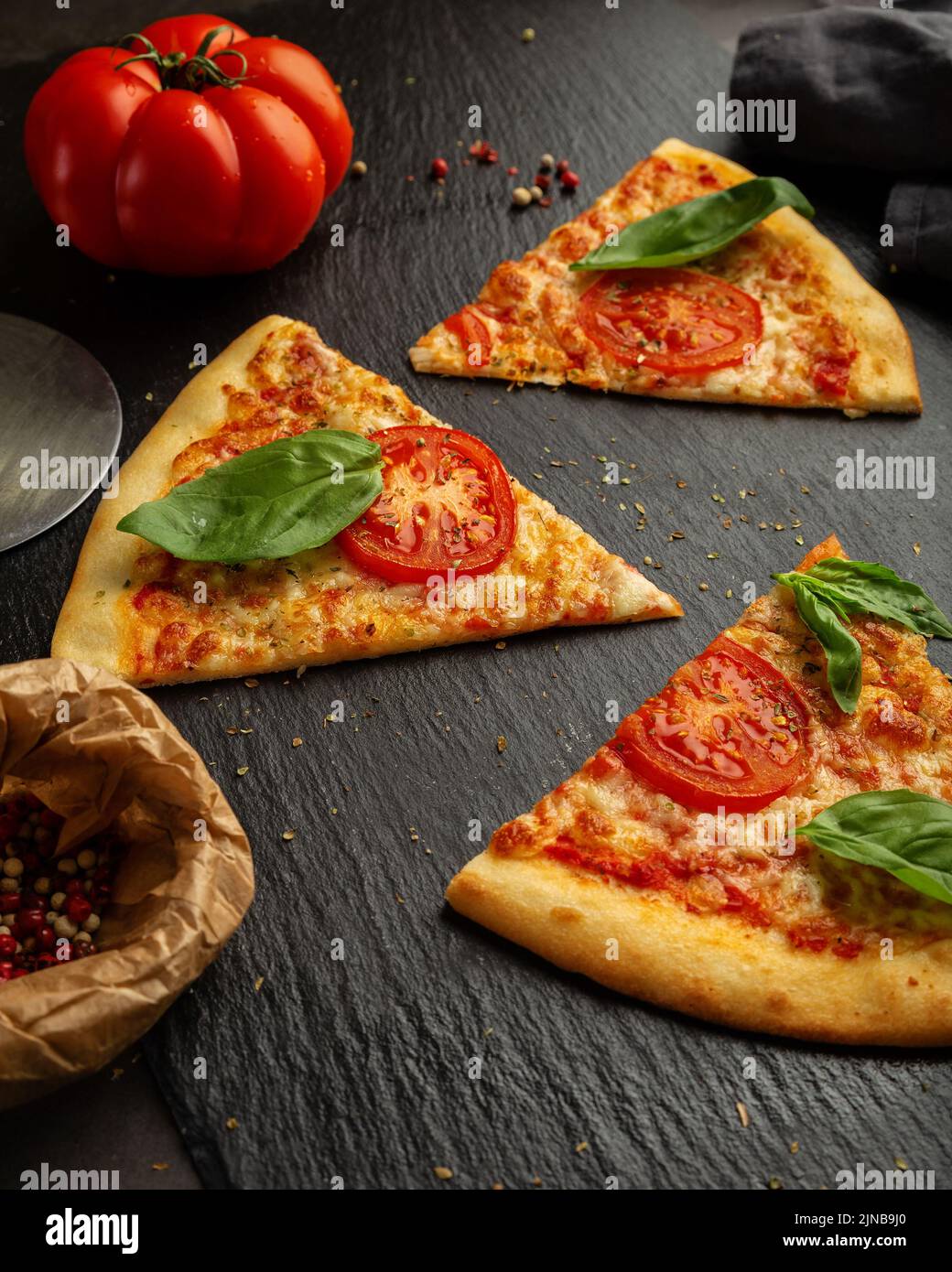 Pieces of pizza on the slate table with ingredients Stock Photo - Alamy