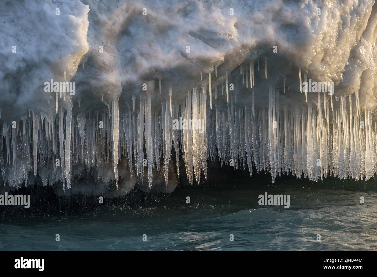 Icicles and snow dripping over water in sunlight Stock Photo - Alamy