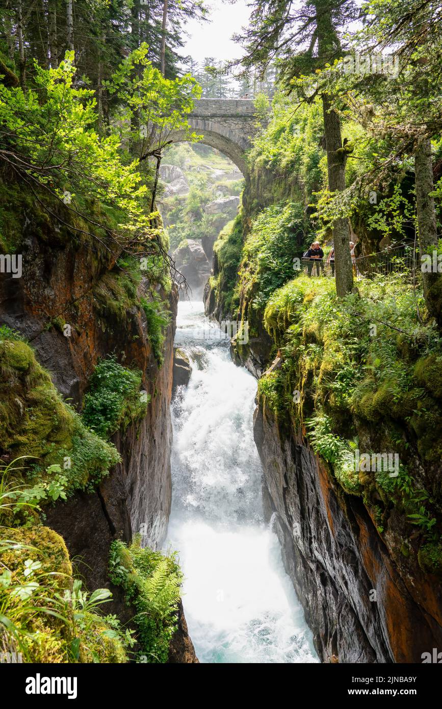a waterfall and river pour through steep-sided rock gorge with white ...