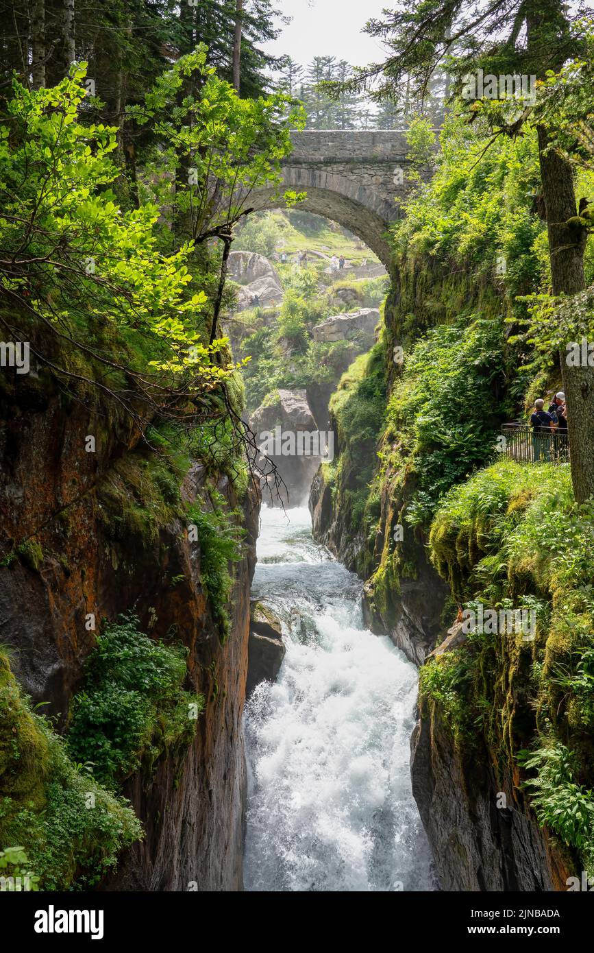 a waterfall and river pour through steep-sided rock gorge with white ...