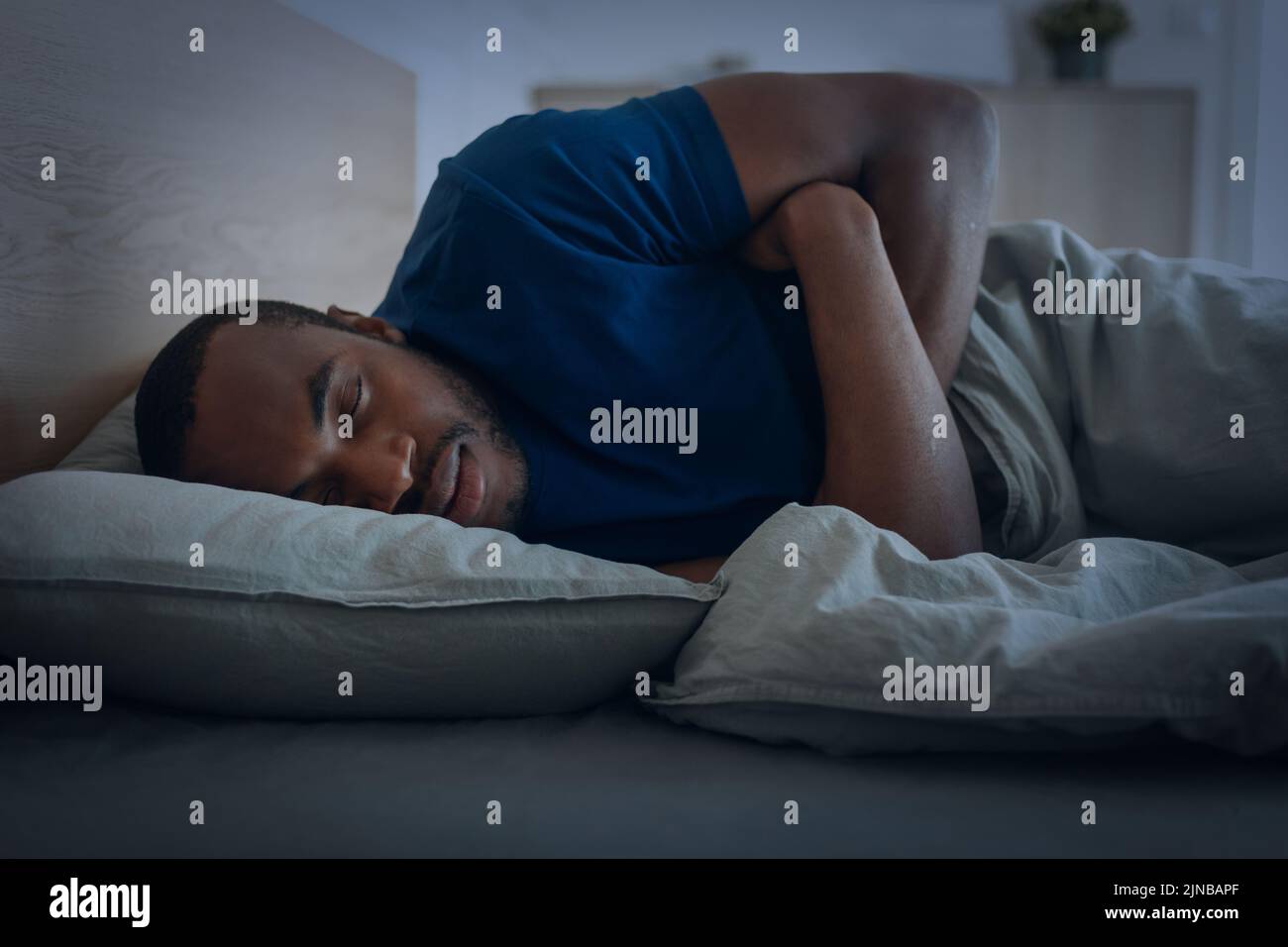 Black Guy Sleeping Lying In Bedroom At Home At Night Stock Photo - Alamy