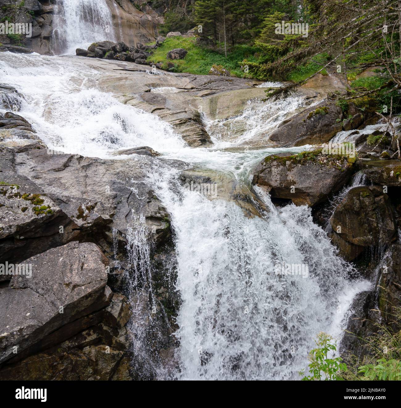 a large teired woodland waterfall, white water crashing over boulders ...