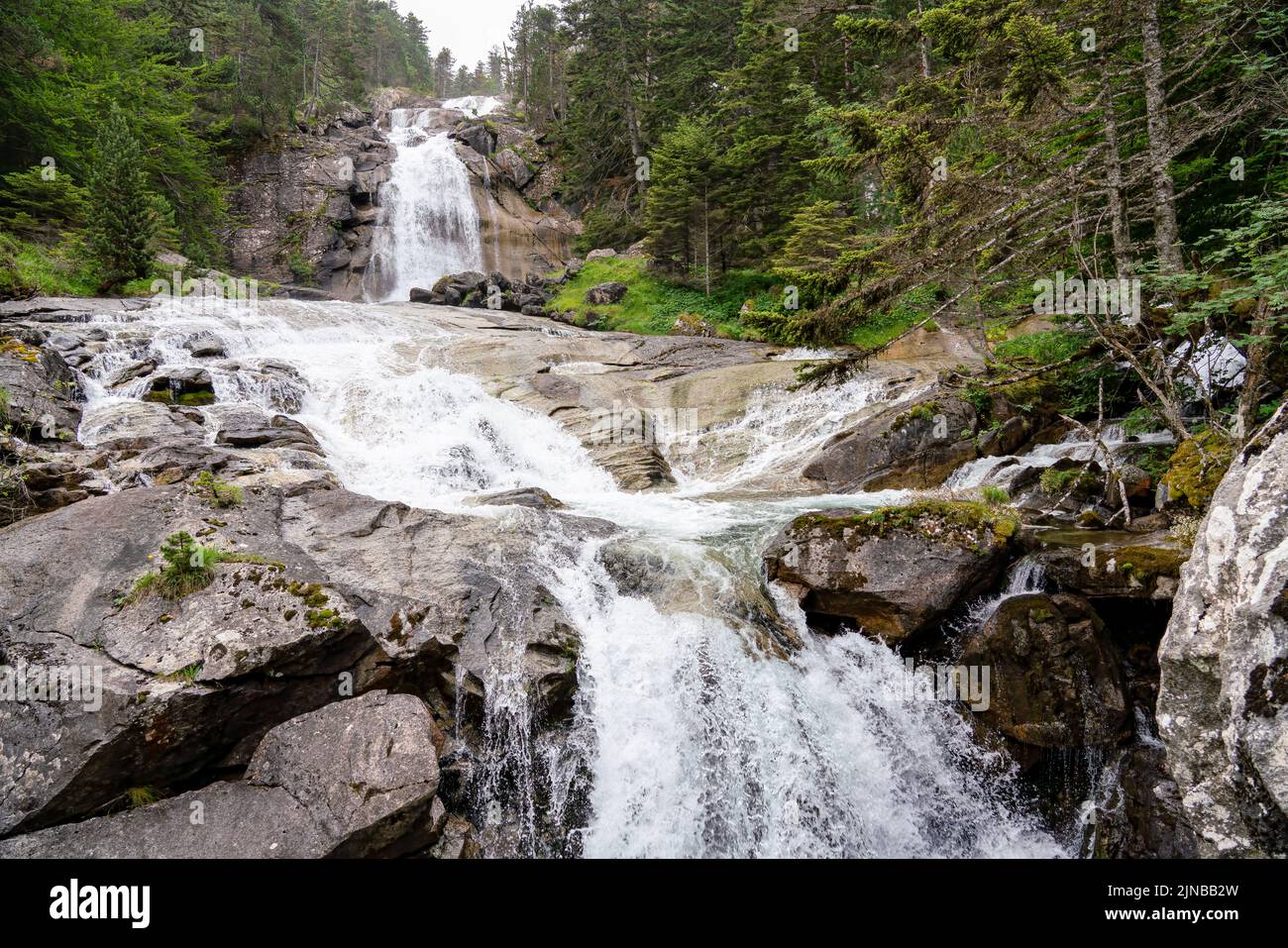 a large teired woodland waterfall, white water crashing over boulders ...