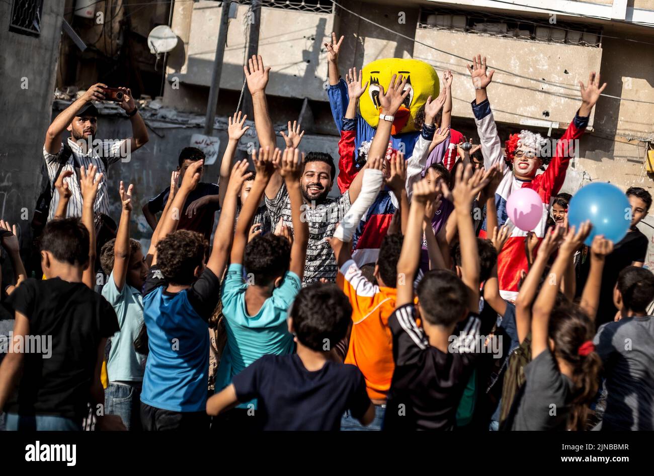 Palestinian clowns entertain children next to rubble of houses ...