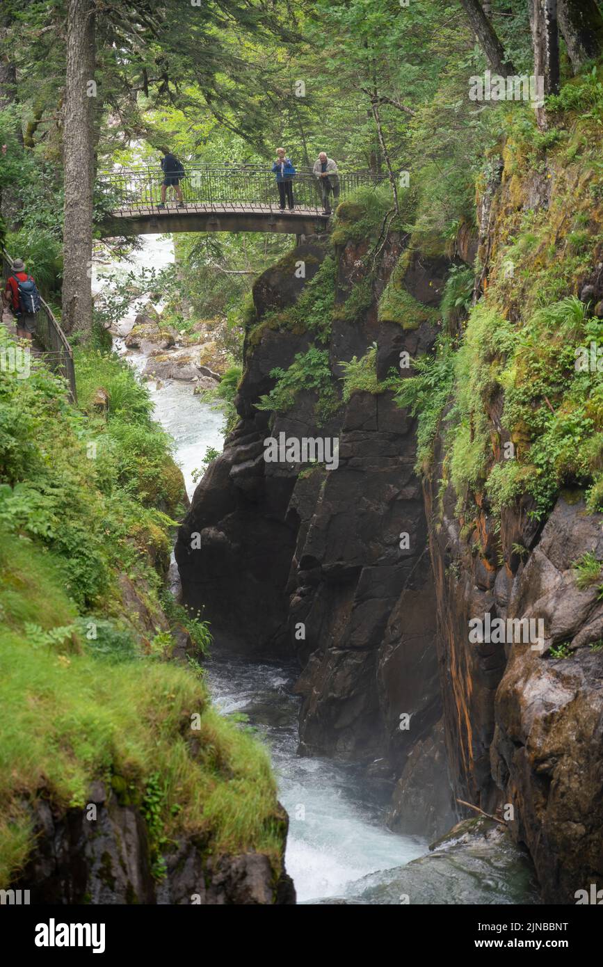 waterfall and river pour through steep-sided rock gorge with white ...