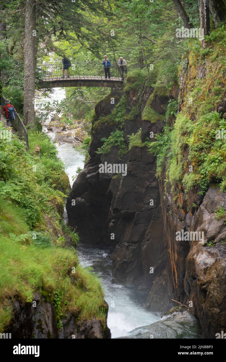 waterfall and river pour through steep-sided rock gorge with white ...
