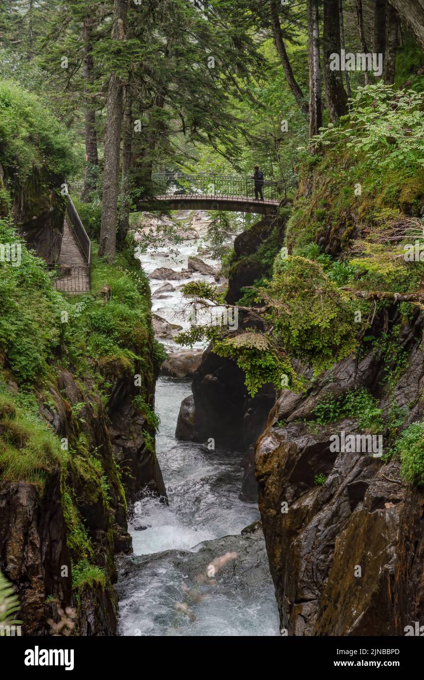 waterfall and river pour through steep-sided rock gorge with white ...