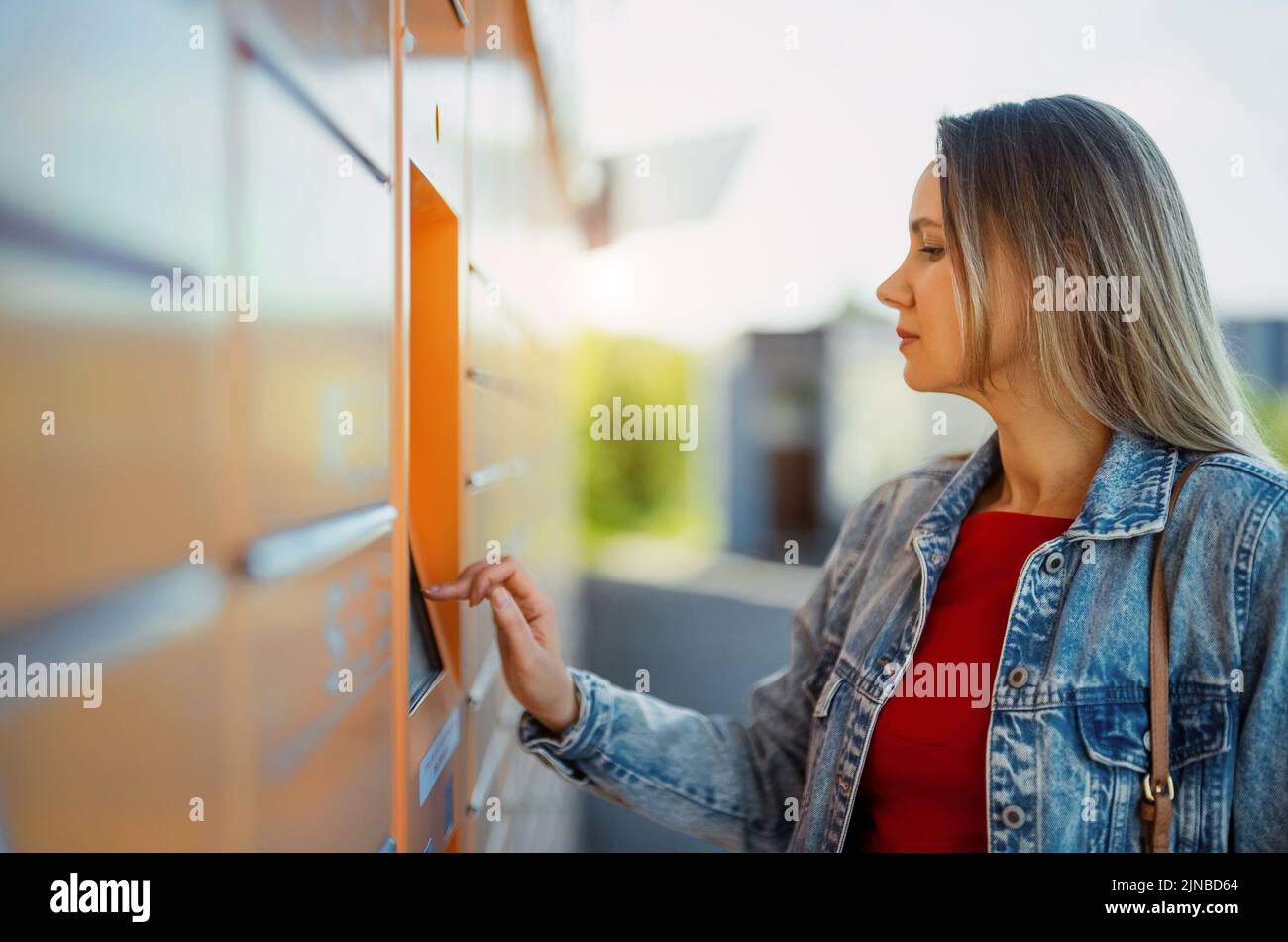 Woman picks up mail from automated self-service post terminal machine ...