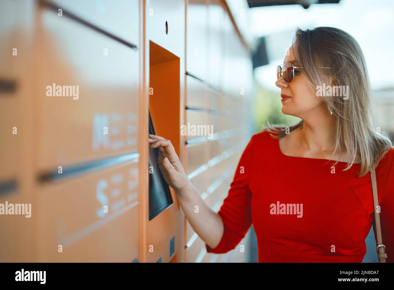 Woman picks up mail from automated self-service post terminal machine ...