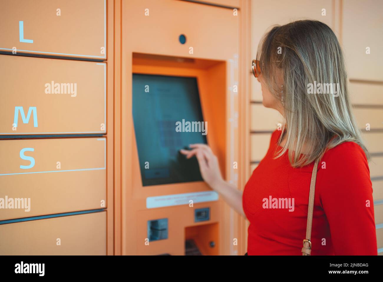 Woman picks up mail from automated self-service post terminal machine ...