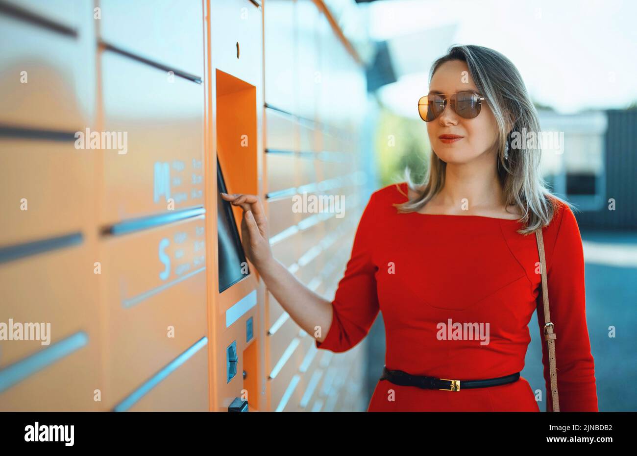 Woman picks up mail from automated self-service post terminal machine ...