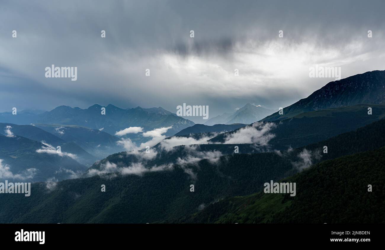 low clouds in and over a green mountain range with tarmac ribbons ...