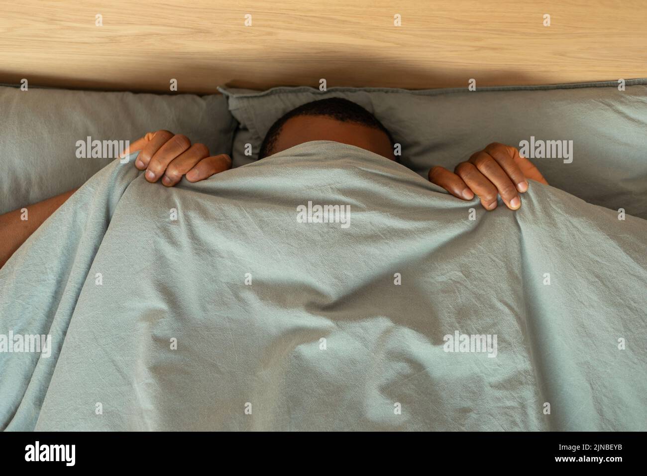 Black Man Hiding Covering Face With Blanket Lying In Bedroom Stock ...