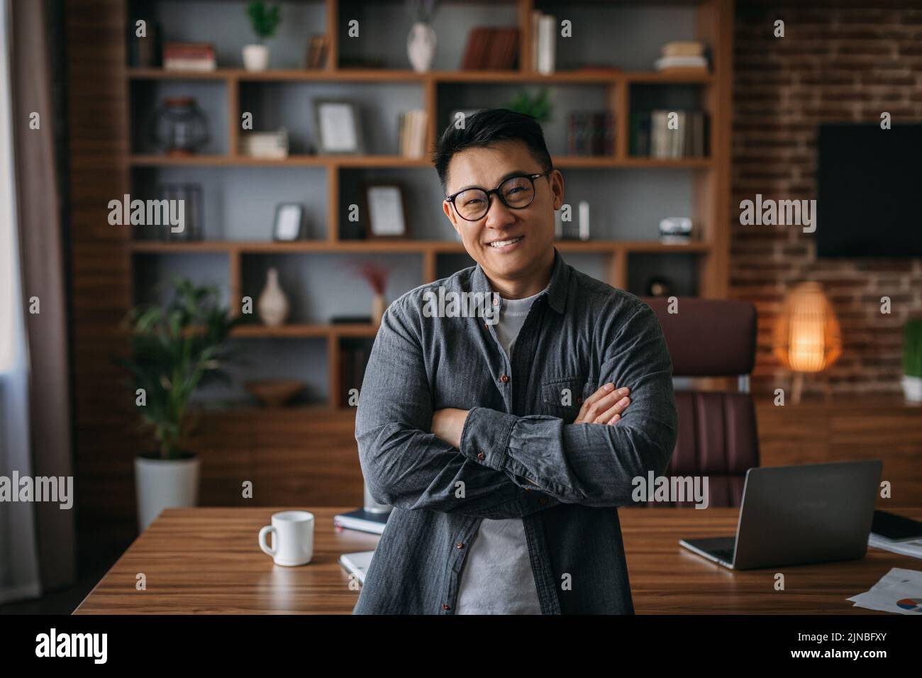 Smiling confident successful adult chinese man in glasses with crossed ...
