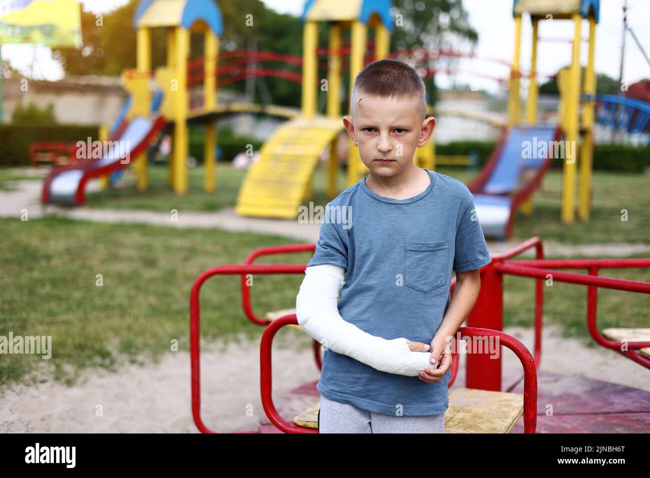 unhappy child with broken limb arm outdoors on playground background ...