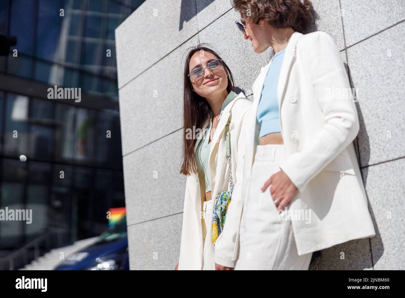 Two women standing near a wall smiling hi-res stock photography and ...