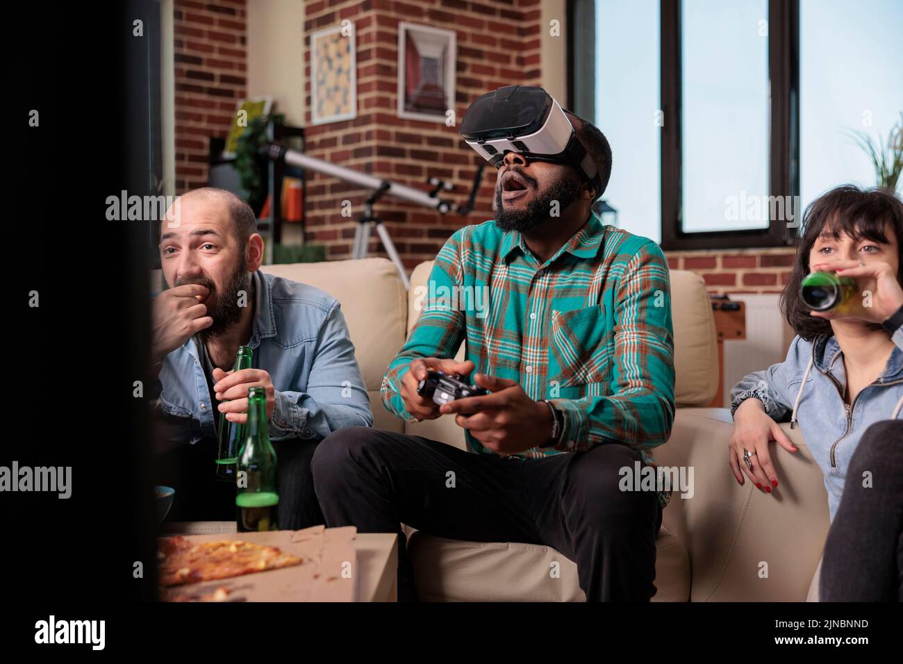 Diverse group of friends using virtual reality headset to play video ...