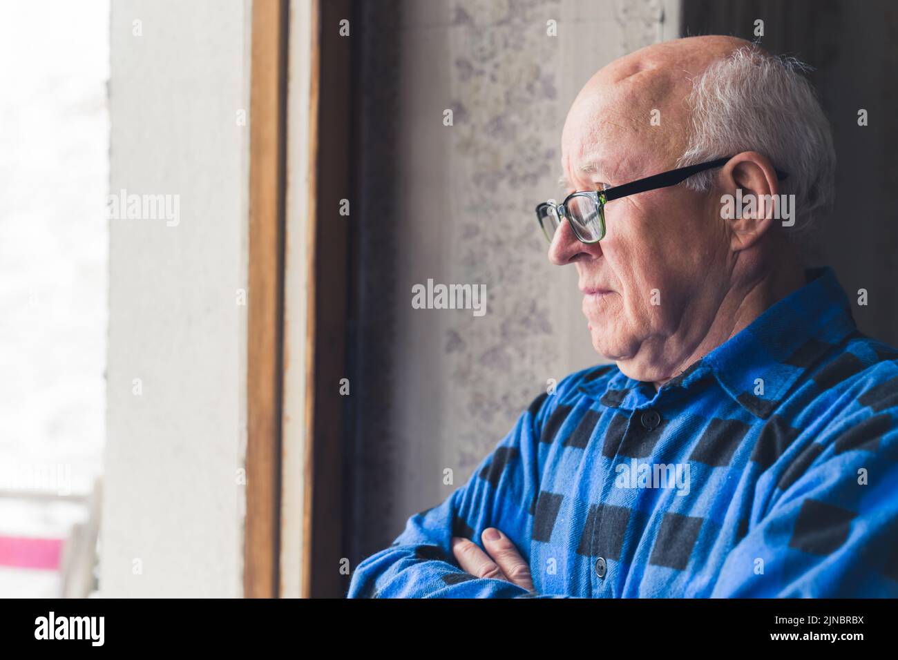 Retired senior bald man with arms crossed, wearing his glasses and ...