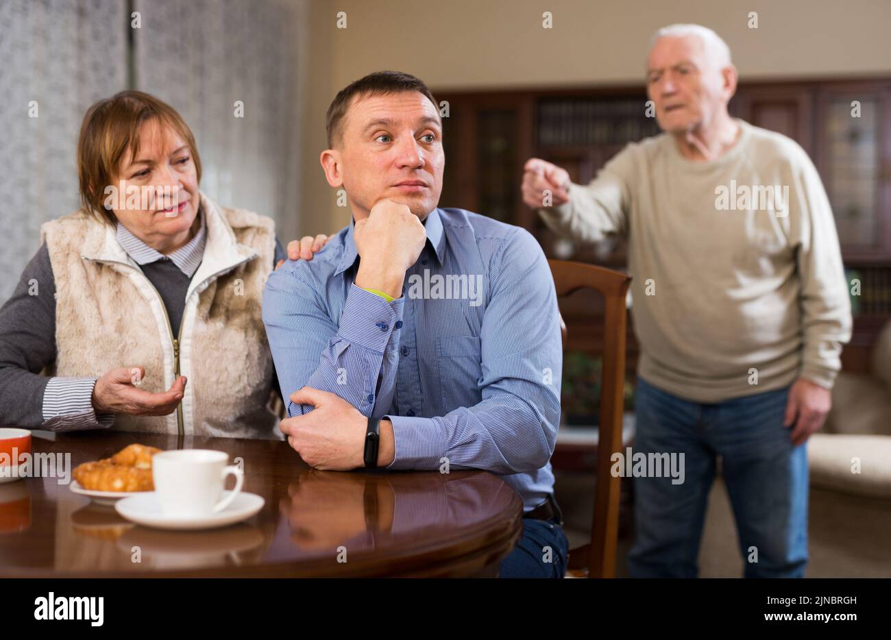 Mother calming adult son during quarrel with father Stock Photo - Alamy