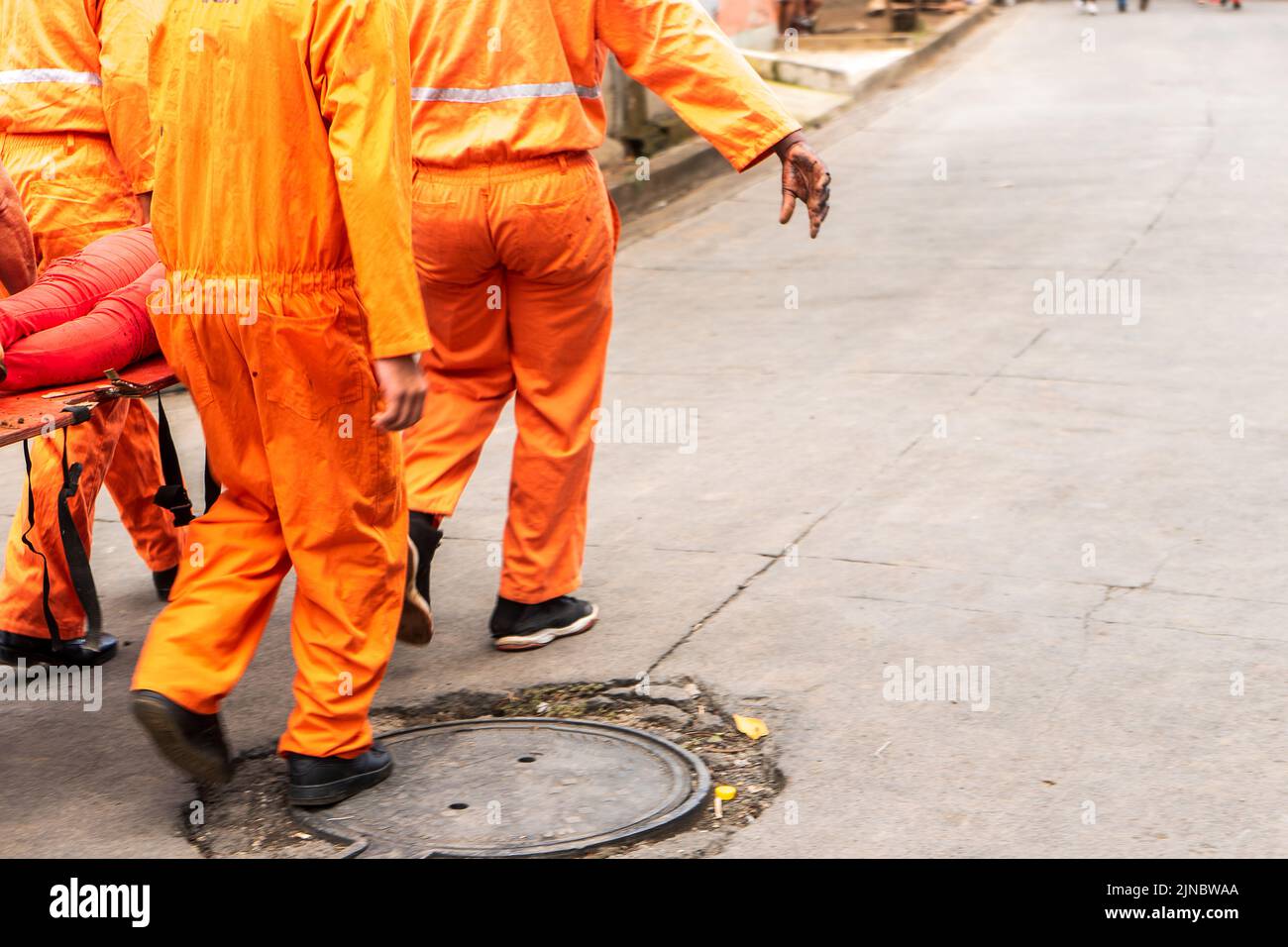 Group of rescuers in orange suit carrying a victim of natural disaster ...