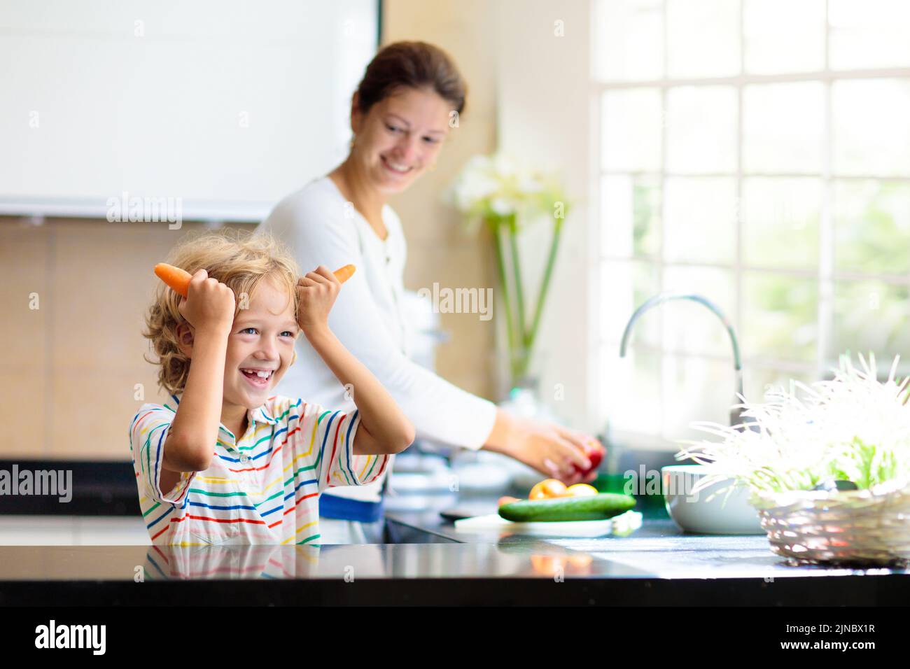 Mother and child make dinner in white kitchen. Family at home. Mom and ...