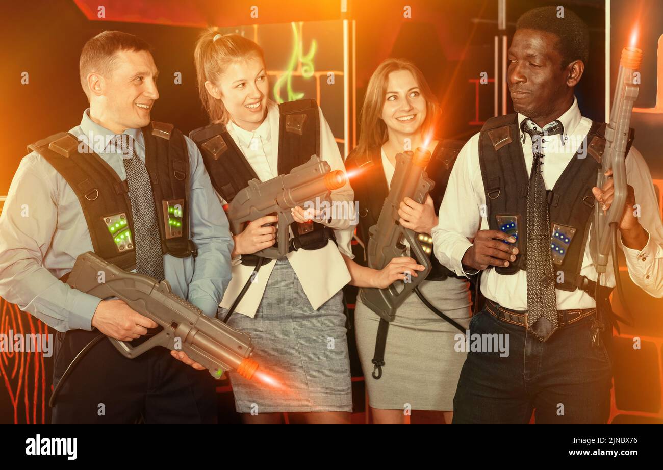Group of glad co-workers holding laser guns Stock Photo - Alamy
