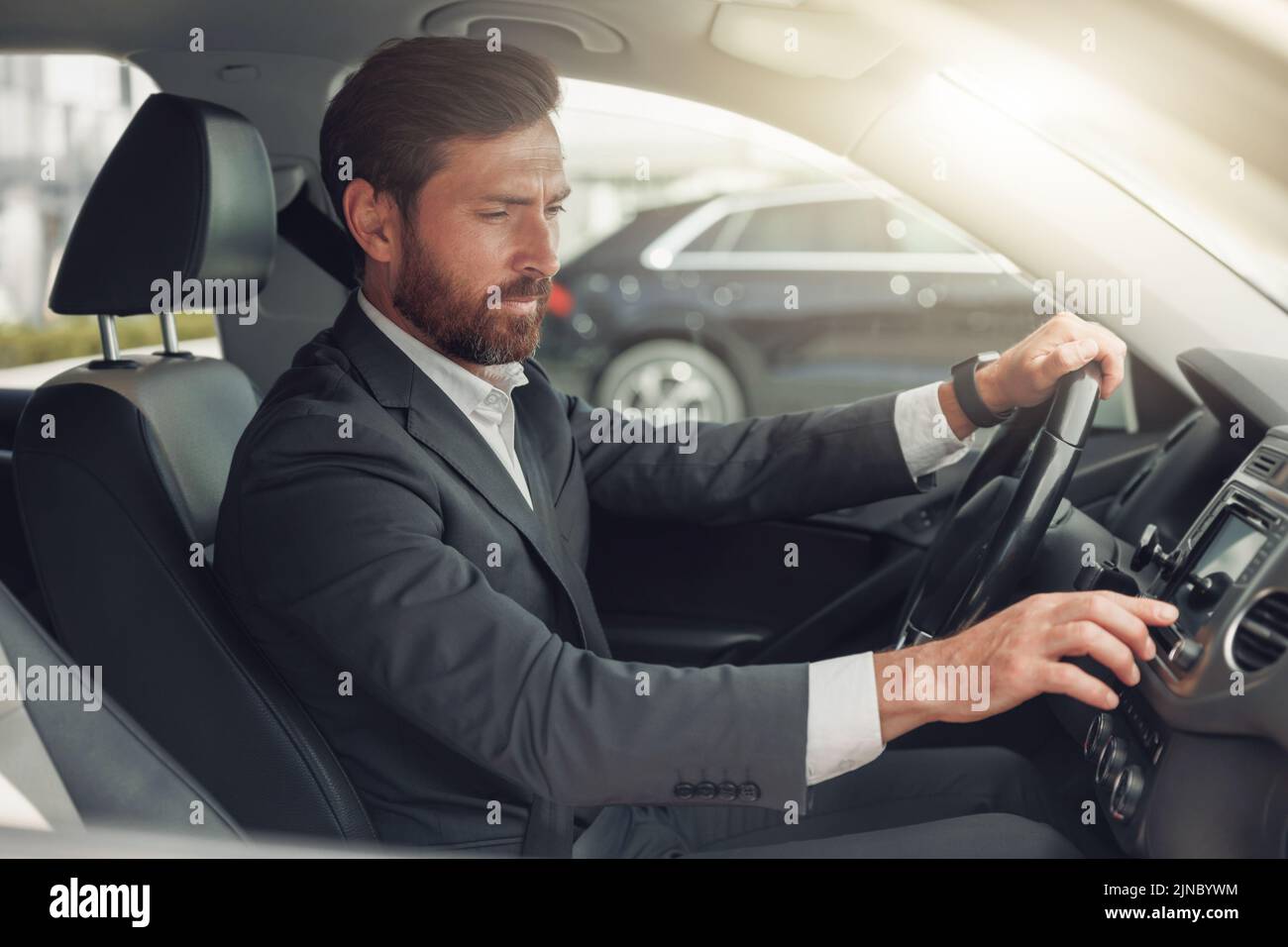 Handsome businessman in grey suit is riding behind steering wheel of ...