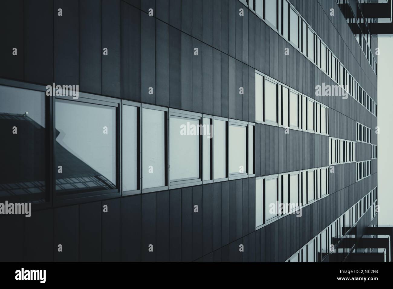 A panoramic shot of a gray office building with windows placed ...