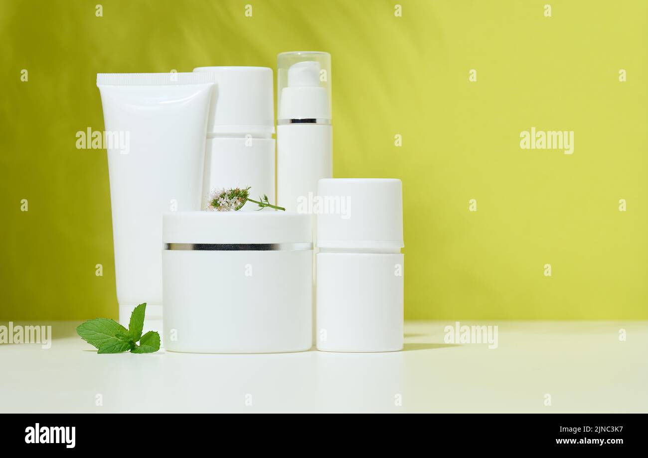 White plastic container tube, a jar with a lid for cosmetics on a green ...