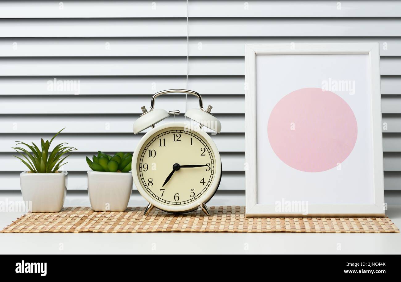Round alarm clock stands on a white table Stock Photo - Alamy