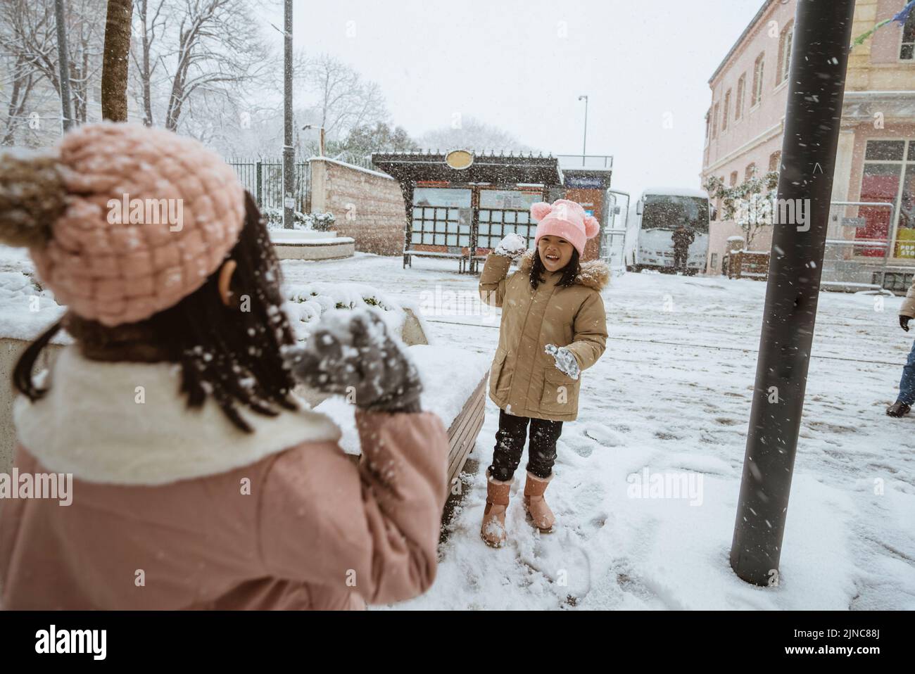 two little girl fighting snow ball in the city Stock Photo - Alamy