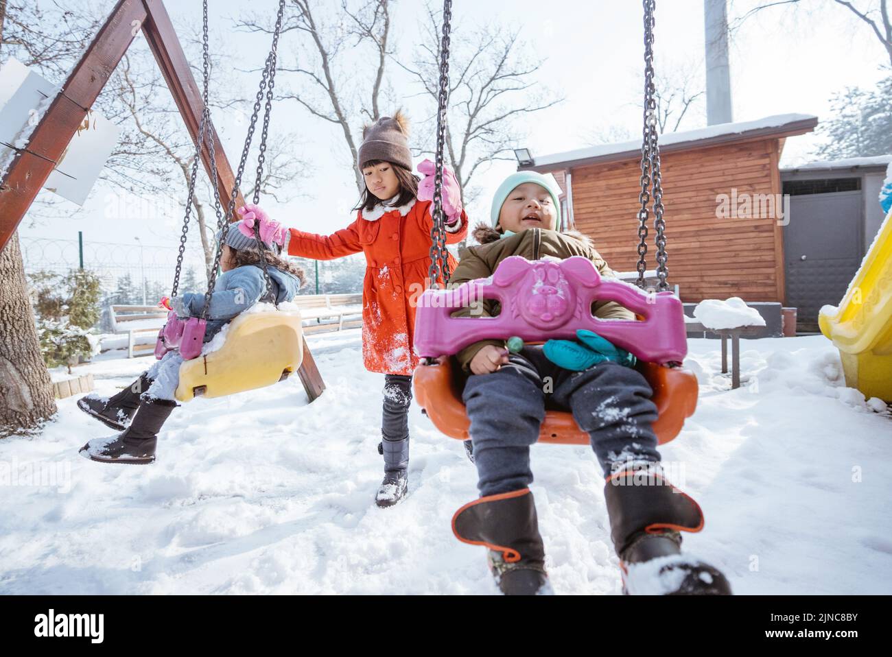 girl help swinging her brother and sister during playing Stock Photo ...