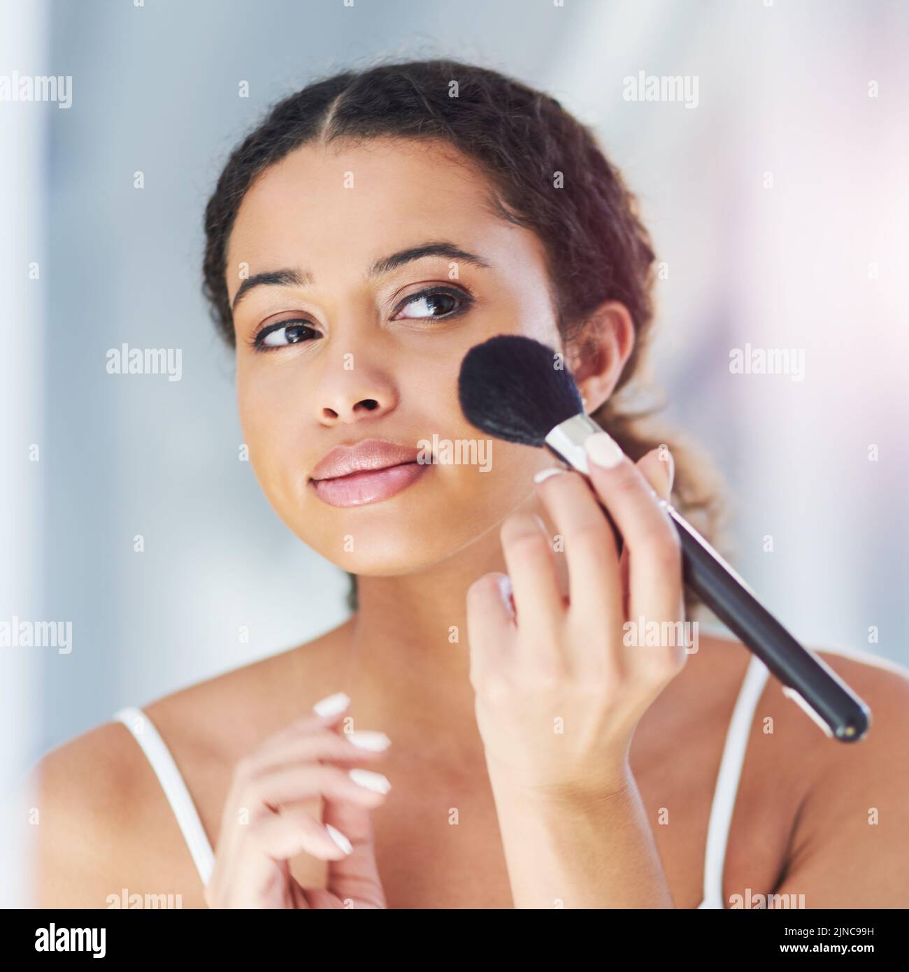Add a dash of glitter to every day. a young woman applying makeup to ...